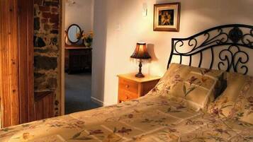 Quarto com cama, mesa de cabeceira, abajur, espelho e um quadro na parede.