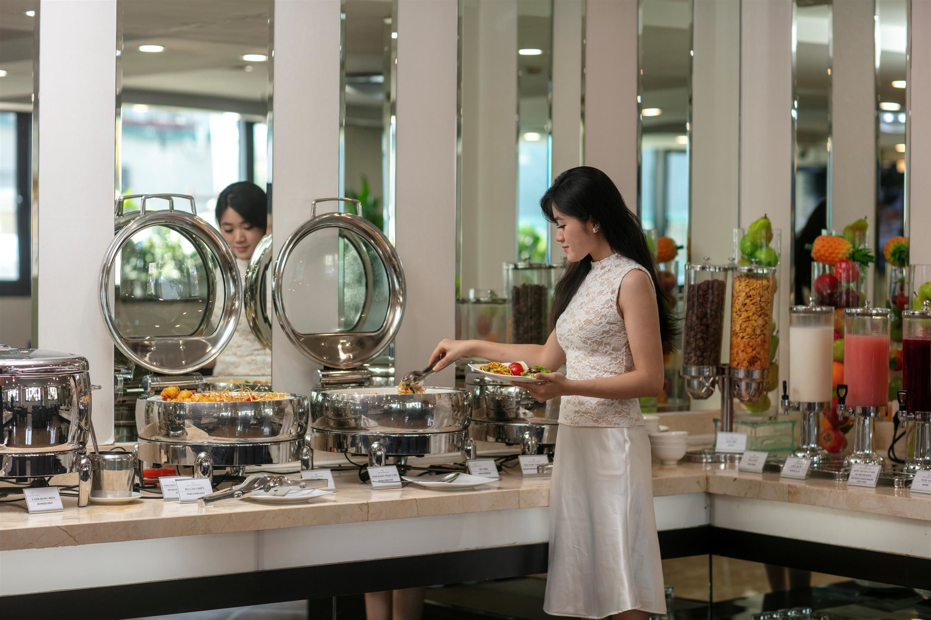 Uma área de buffet com diversas estações de comida e uma pessoa se servindo.