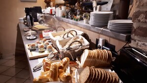 Buffet com diversos pães, pastelaria e uma estação de café.