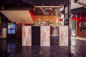 Uma área de bar com balcão de mármore, geladeira e máquina de vendas.