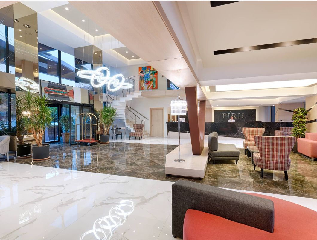 Um lobby moderno com piso de mármore, balcão de recepção e áreas de estar.