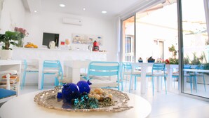 Uma sala de jantar luminosa e moderna, com mobiliário branco e cadeiras azuis, destacando uma bandeja decorativa com ornamentos.