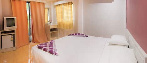 Quarto de hotel com cama, escrivaninha, televisão e ar condicionado.