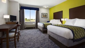 Quarto de hotel com duas camas, uma mesa e uma televisão.