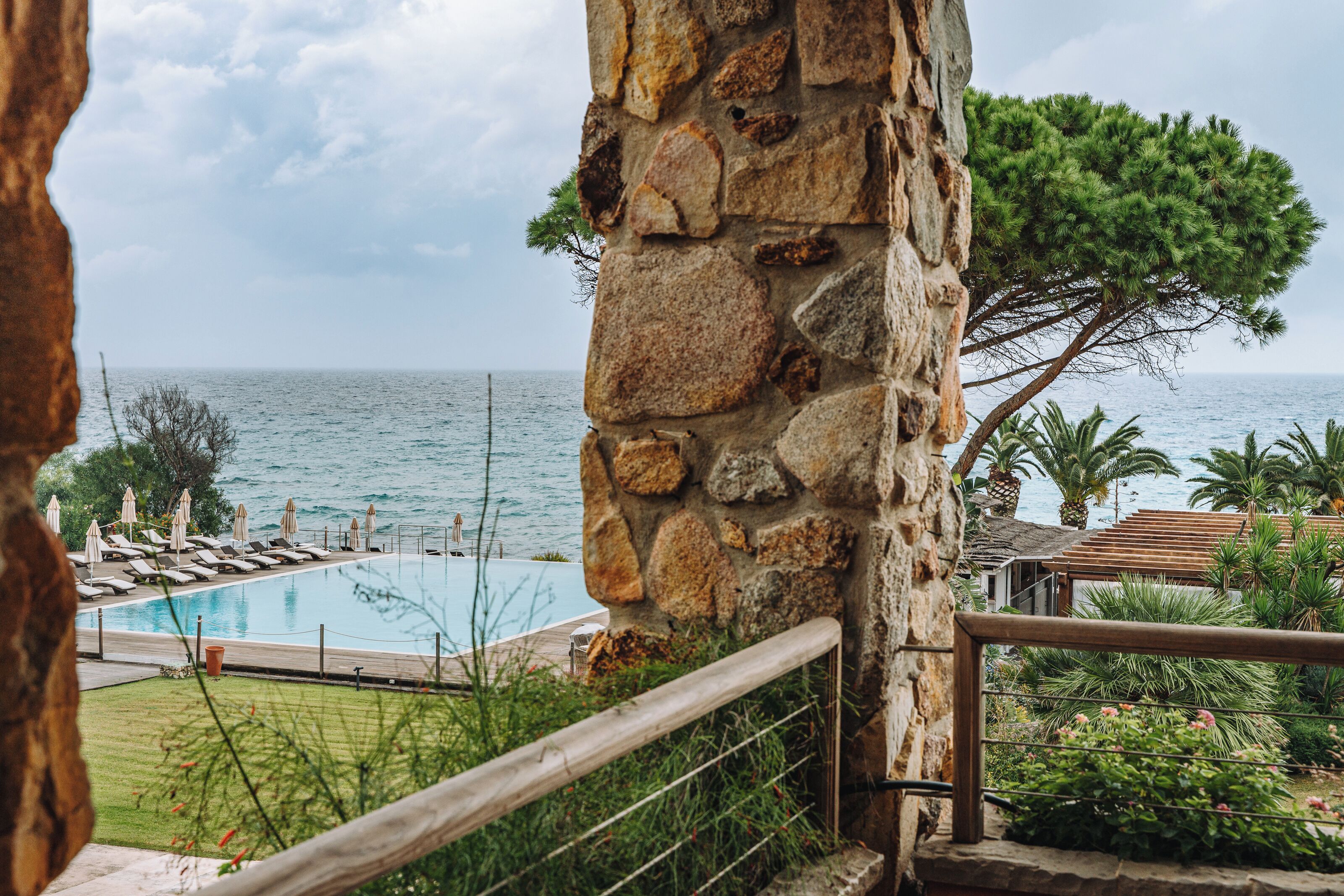 Mural de pedra, uma piscina e vista para o mar.