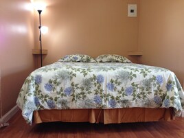 Cama com roupa de cama florida, luminária de cabeceira e interruptor de luz na parede.