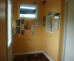 Um corredor com um mural, uma janela e uma placa com a inscrição 'OFFICE'.