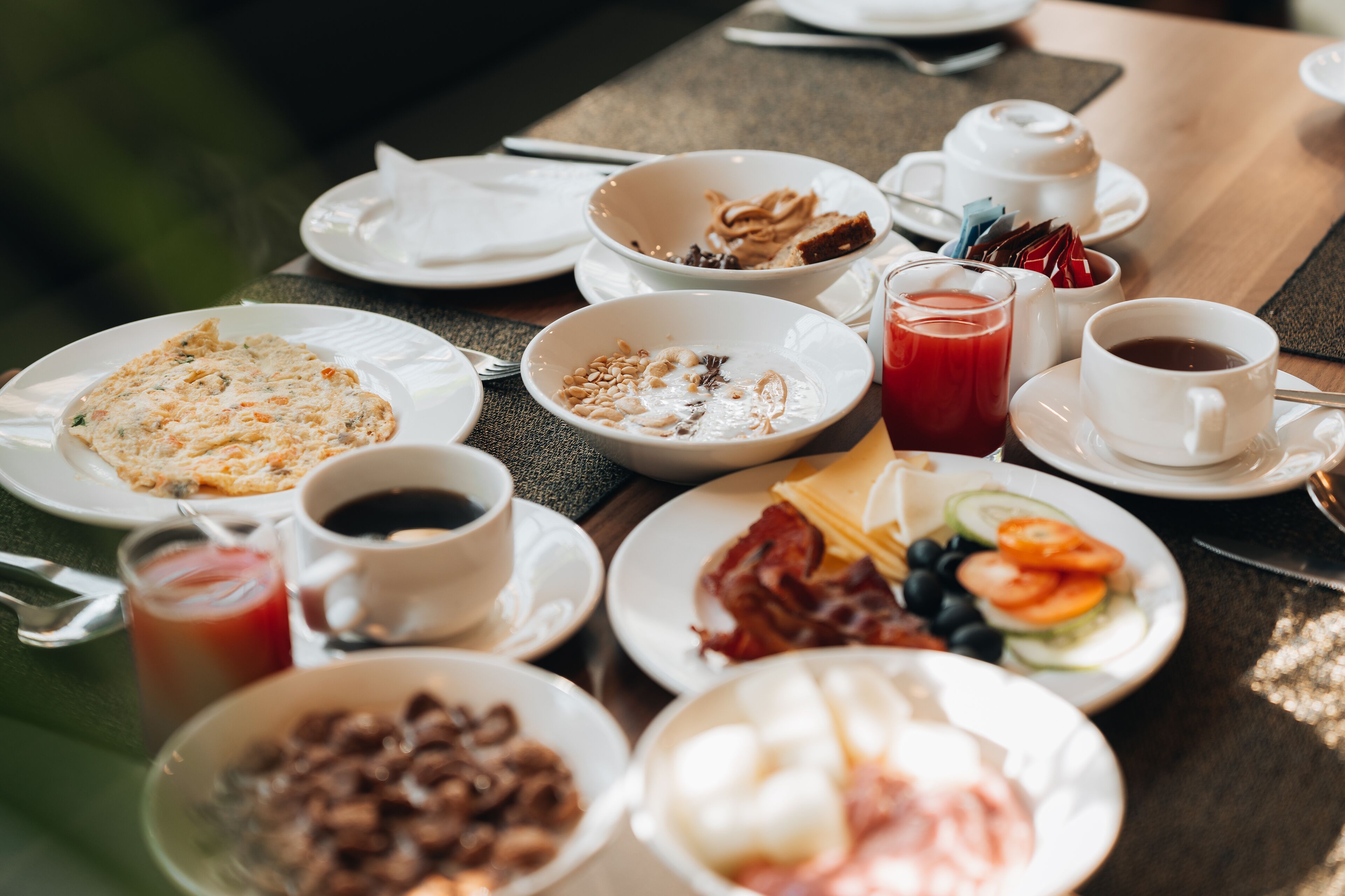 Uma mesa de café da manhã com diversos pratos, incluindo ovos, bacon e torradas.