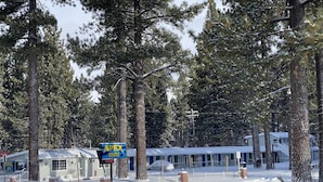 Paisagem coberta de neve com um motel chamado 'Apex Inn', apresentando uma fileira de cabanas e uma placa.