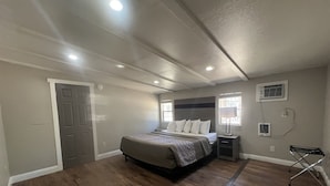 Quarto com cama, mesa de cabeceira, abajur e uma cadeira.