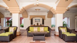 Um hall amplo com um conjunto de sofás central, duas poltronas e uma mesa de centro.