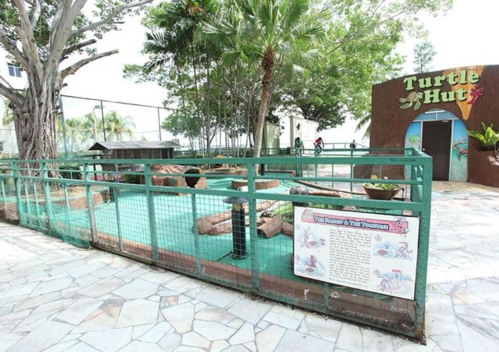 Uma área cercada com uma placa indicando 'Turtle Hut' e uma outra placa com informações.