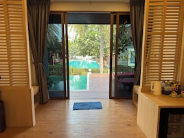 Quarto com vista para uma piscina, piso de madeira e um banco.
