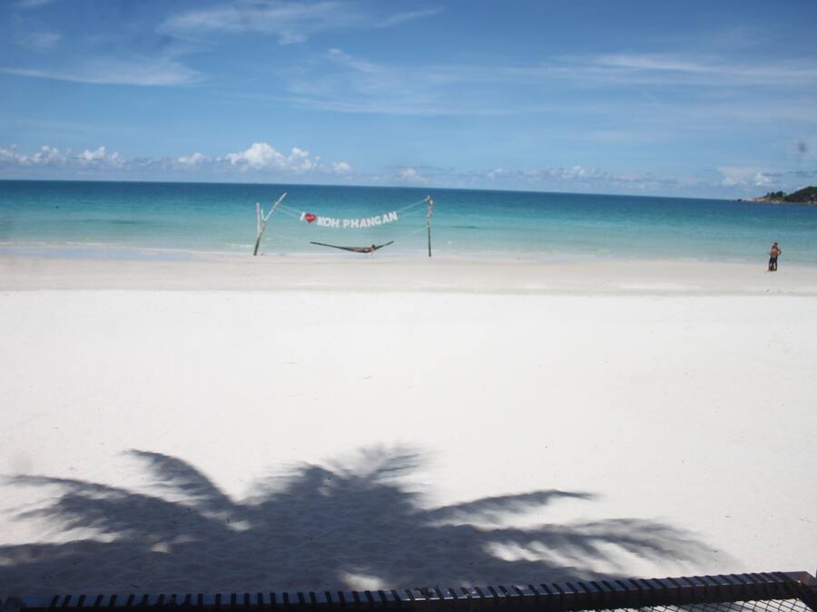 Uma praia com uma rede e uma placa que diz "Koh Phangan".
