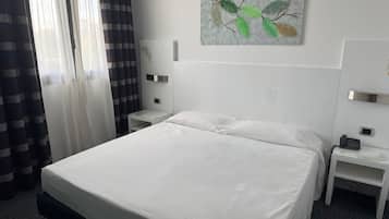 Quarto de hotel com uma cama grande, uma mesinha de cabeceira com telefone e uma obra de arte na parede.