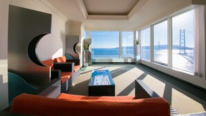 Quarto de hotel moderno com uma grande janela que oferece vista para uma ponte e para o mar.