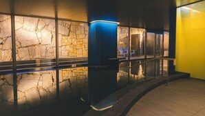 Interior moderno com paredes de pedra, um pilar azul e uma porta de vidro que dá para a área do chuveiro.