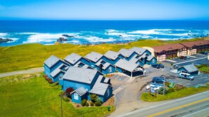 Um hotel à beira-mar com vários edifícios azuis, uma área de estacionamento e vista para o oceano.