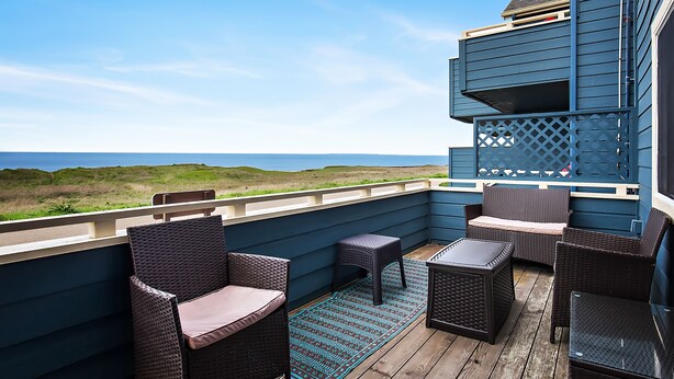Um terraço com móveis de vime e vista para a praia.