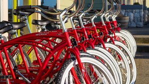 Uma fileira de bicicletas vermelhas estacionadas em frente a um edifício com porta e janelas verdes.