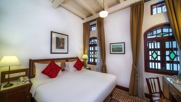 Um quarto bem arrumado, com uma cama, mesas de cabeceira, escrivaninha e uma cadeira.