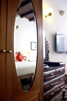 Quarto de hotel com um espelho grande, cómoda de madeira e televisão fixada na parede.