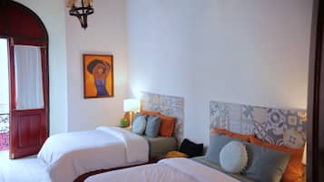 Quarto de hotel com duas camas, um quadro na parede e um candelabro.