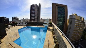 Piscina no terraço com vista ampla dos edifícios ao redor.