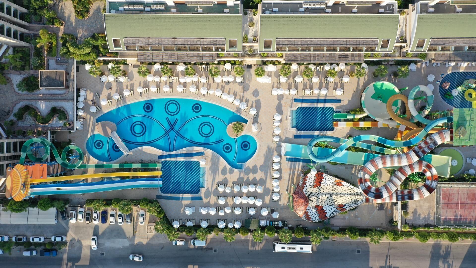 Vista aérea de um resort com uma piscina grande, toboáguas e áreas de estar ao ar livre.