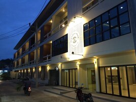 Um hotel com vários andares, uma placa visível e uma entrada bem iluminada.