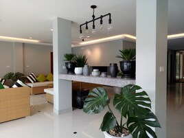 Uma sala de estar moderna com um sofá, uma mesa de centro e um espaço de jantar com bancada e plantas em vasos.