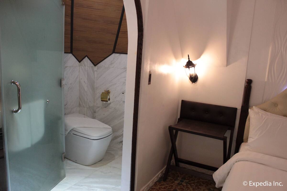 Um banheiro com vaso sanitário, um banco e luminária fixada na parede.