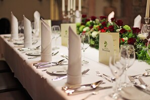 Mesa posta para um jantar formal, com toalha branca, talheres e copos.