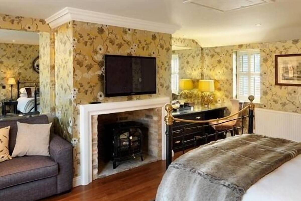 Quarto com lareira, sofá, cama e televisão.