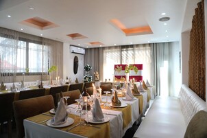 Restaurante com mesas compridas preparadas para refeições, com velas e elegantes arranjos de mesa.