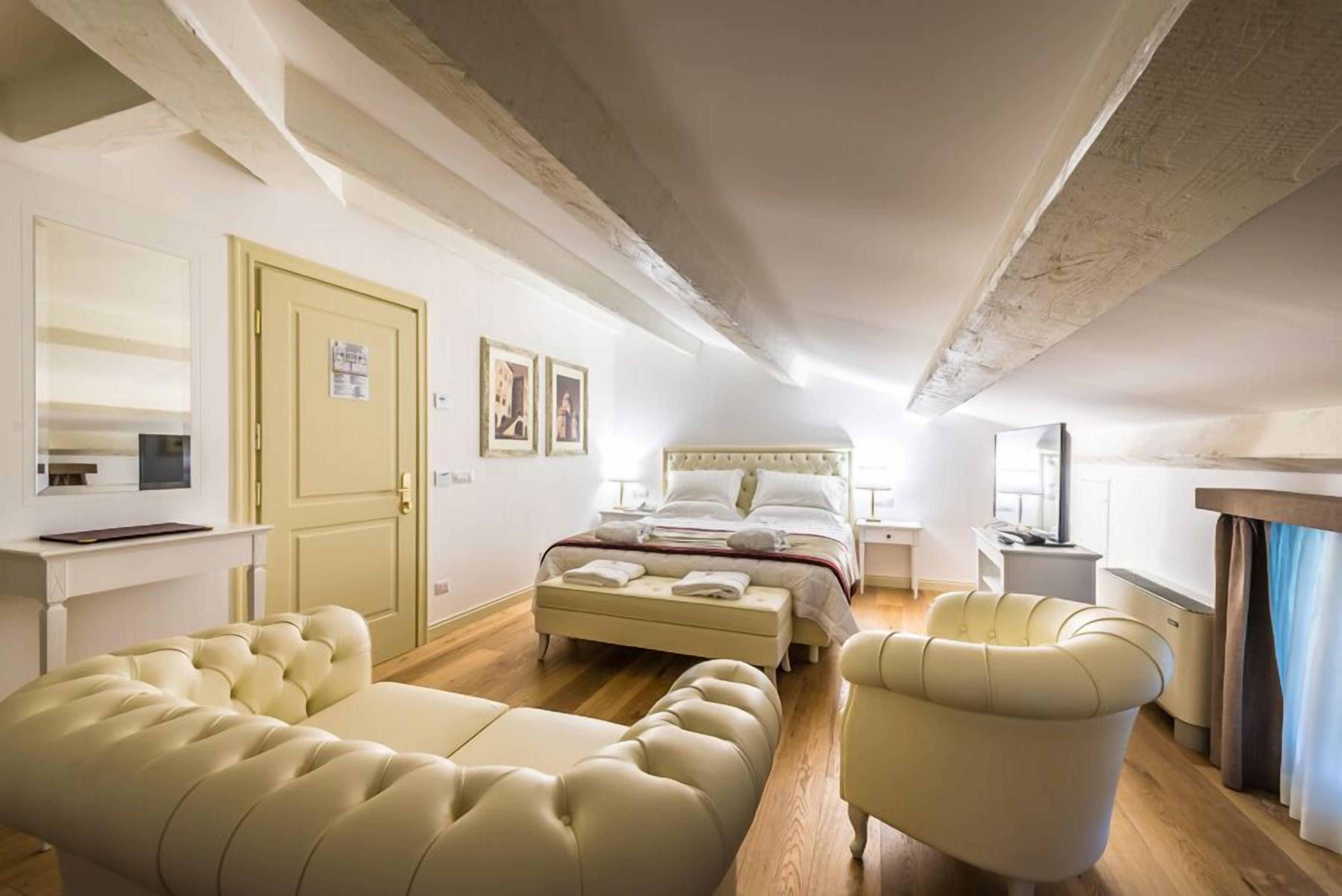 Quarto com cama, duas mesas de cabeceira, escrivaninha e duas poltronas.