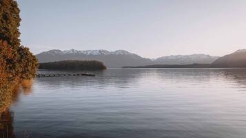 Um lago tranquilo com um cais que se estende sobre a água, rodeado por montanhas e árvores.