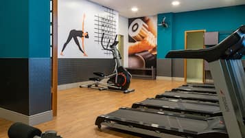 Uma academia com esteiras, bicicleta ergométrica e halteres.