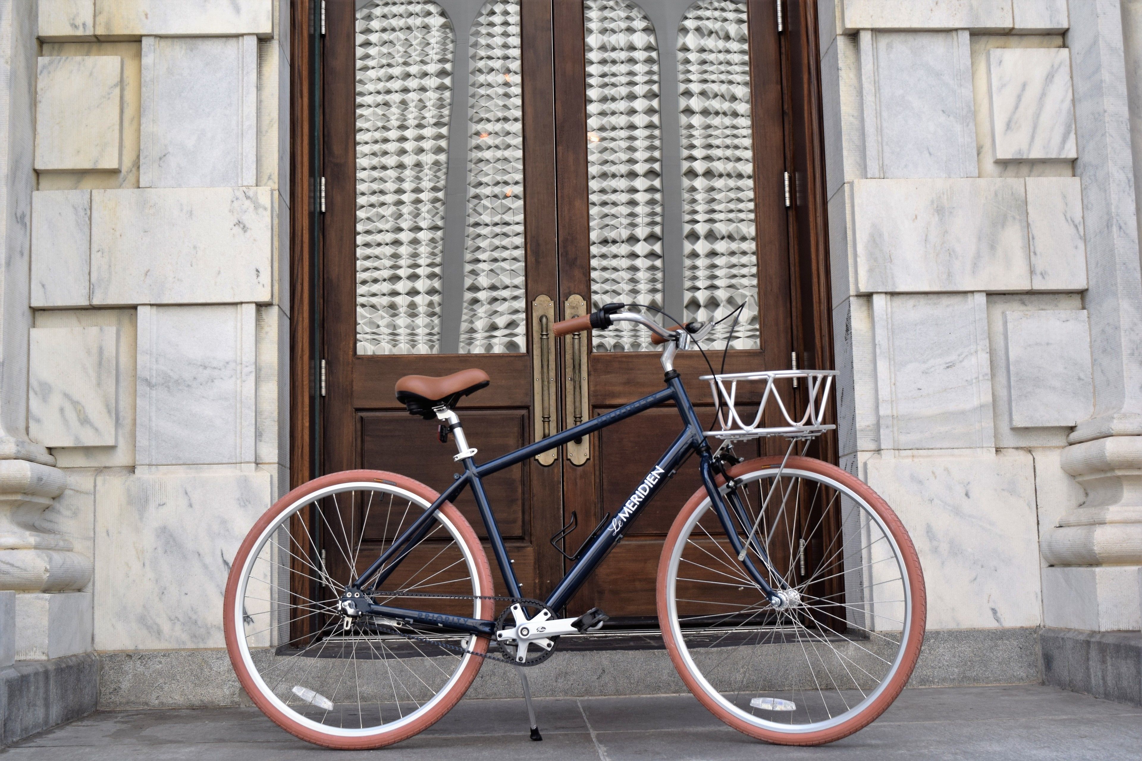 Uma bicicleta estacionada em frente a um edifício com uma porta de madeira grande e janela com padrão.