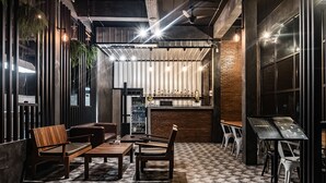 Uma área de bar com móveis de madeira, chão xadrez e parede de tijolos.