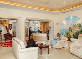 Uma área de recepção com recepcionista, um homem e uma mulher sentados na sala de estar.