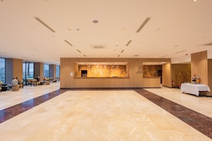 Um hall amplo com balcão de atendimento, área de estar e mesa com dispensador de bebidas.