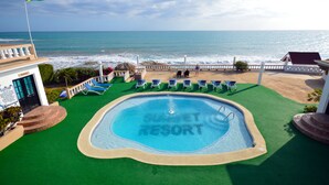 Um resort com piscina, cadeiras de praia e vista para o oceano.