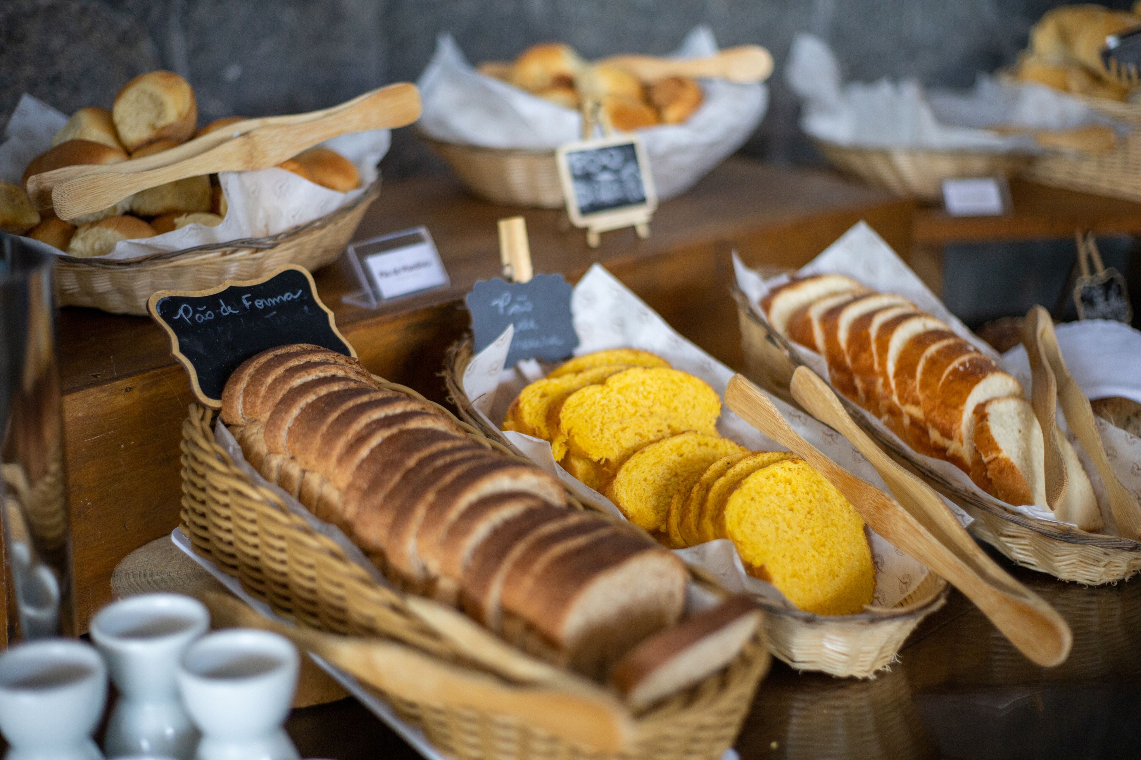 Diversos tipos de pão expostos em cestas sobre uma mesa.