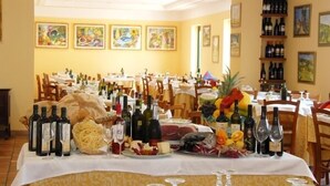 Restaurante com várias mesas preparadas para refeições, exibindo diversos pratos e garrafas de vinho.
