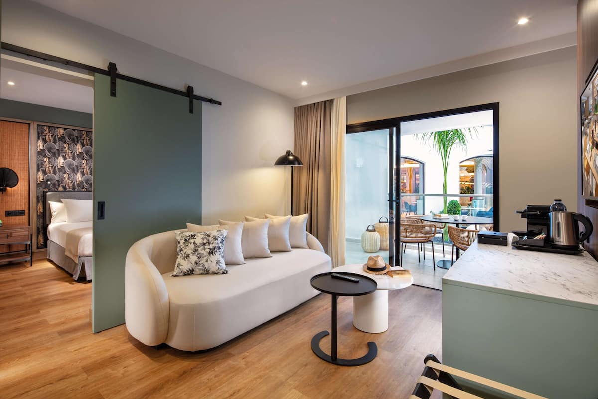 Uma sala de estar moderna com sofá, mesa de centro e área de cozinha com bancada e eletrodomésticos.