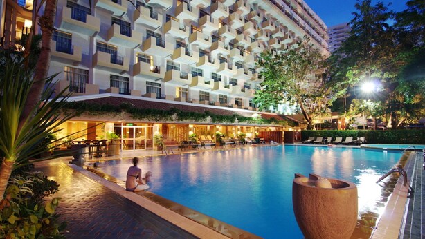 Um hotel com piscina, área de estar externa e fachada bem iluminada.