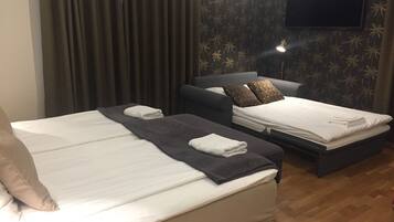 Quarto de hotel com duas camas, uma televisão de tela plana na parede e piso de madeira.