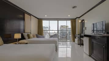 Quarto de hotel com duas camas, uma escrivaninha, televisão e varanda com vista para a cidade.