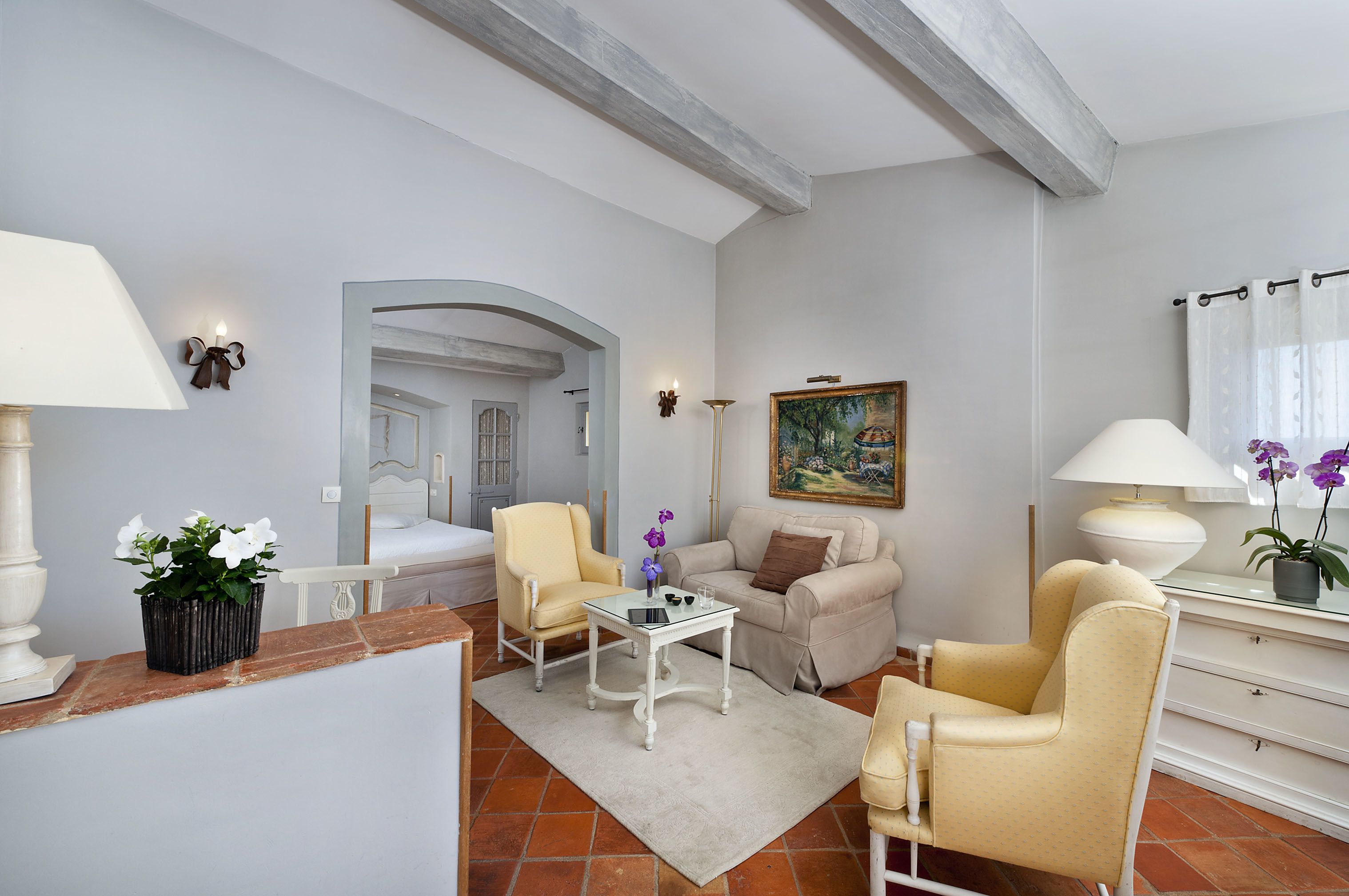 Uma sala de estar com sofá, poltronas, mesa de centro e um quadro na parede.